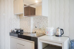 Uma pequena cozinha compacta com bancada preta, pia, cafeteira e chaleira.