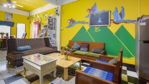 Uma sala de estar vibrante, com sofás listrados, uma mesa de centro e uma televisão fixada na parede.