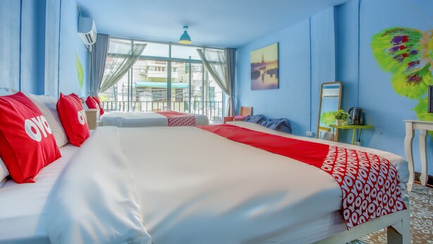 Quarto de hotel com duas camas, uma janela grande, vista para edifícios e um quadro na parede.