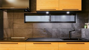 Uma cozinha moderna com ladrilhos de pedra escura, armários de madeira e bancada preta.