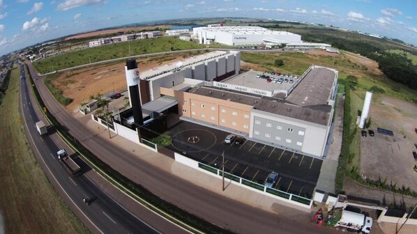Uma zona industrial com um edifício grande, estacionamento e uma autoestrada.