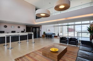 Um lobby moderno com balcão de recepção, área de estar e grandes janelas.