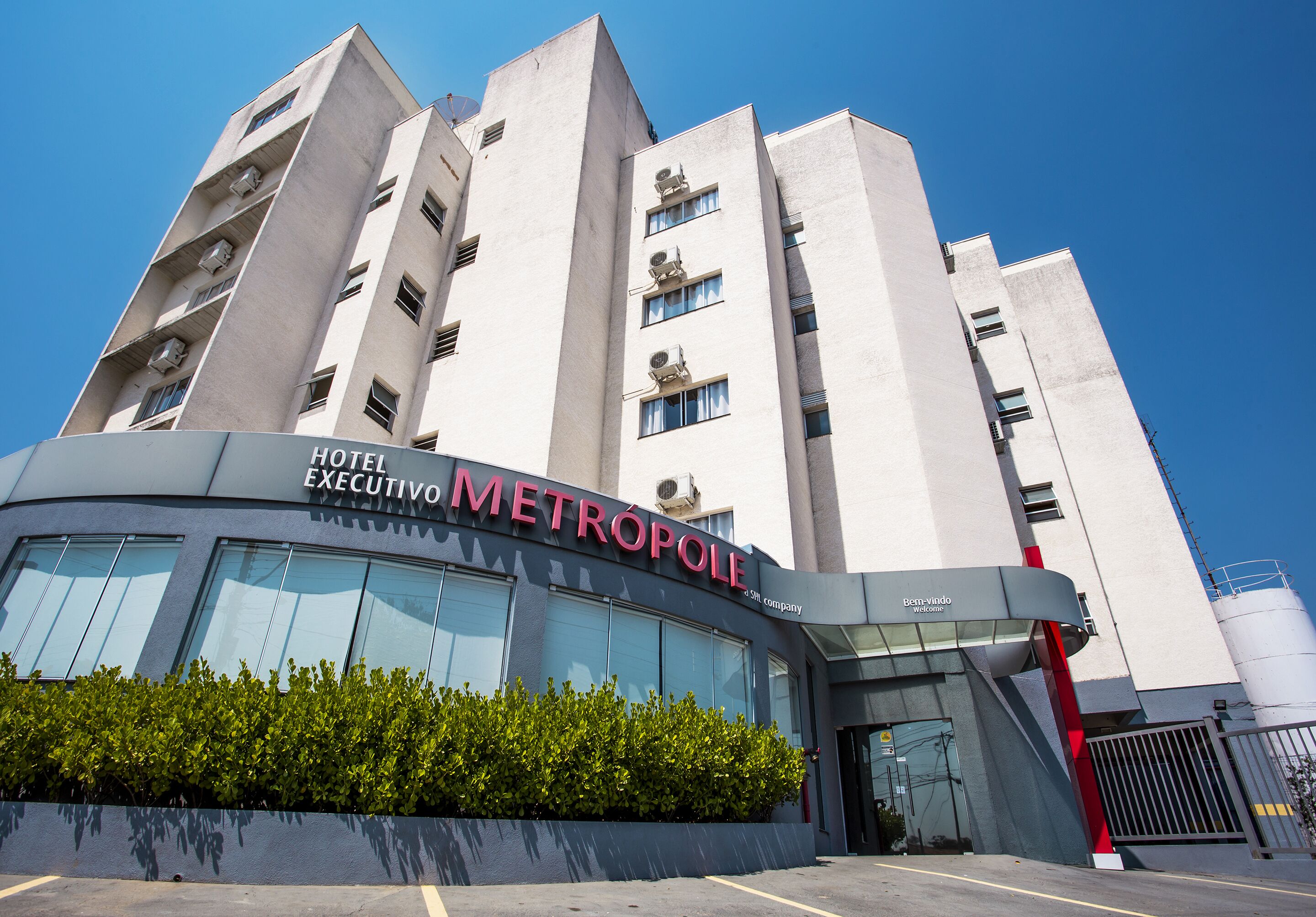 Um hotel moderno com um letreiro chamativo 'METROPOLI', grandes janelas e um céu claro.