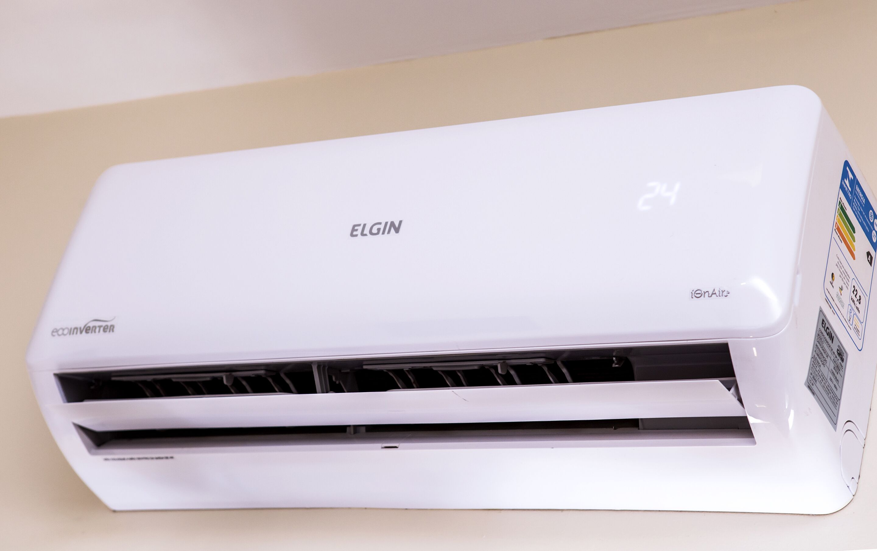 Um aparelho de ar condicionado ELGIN branco com uma saída de ar frontal e painel de controle no lado direito.