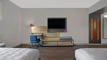 Quarto de hotel com duas camas, uma escrivaninha com cadeira, televisão de tela plana na parede e um armário de madeira.