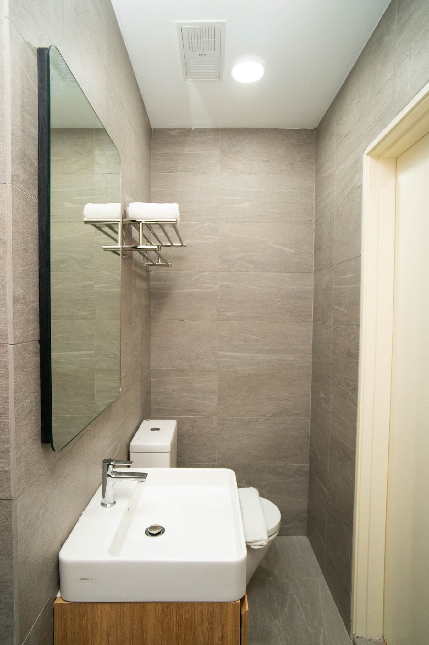 Casa de banho compacta com lavatório branco, sanita e espelho.