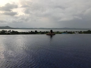 Uma pessoa em uma piscina grande e vazia, com vista para montanhas distantes e um céu nublado.