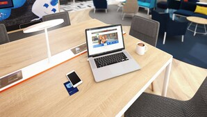 Um laptop sobre uma mesa de madeira, com um smartphone e uma xícara de café ao lado.