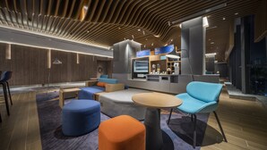 Um lobby moderno com áreas de estar, balcão de recepção e vista para a cidade.