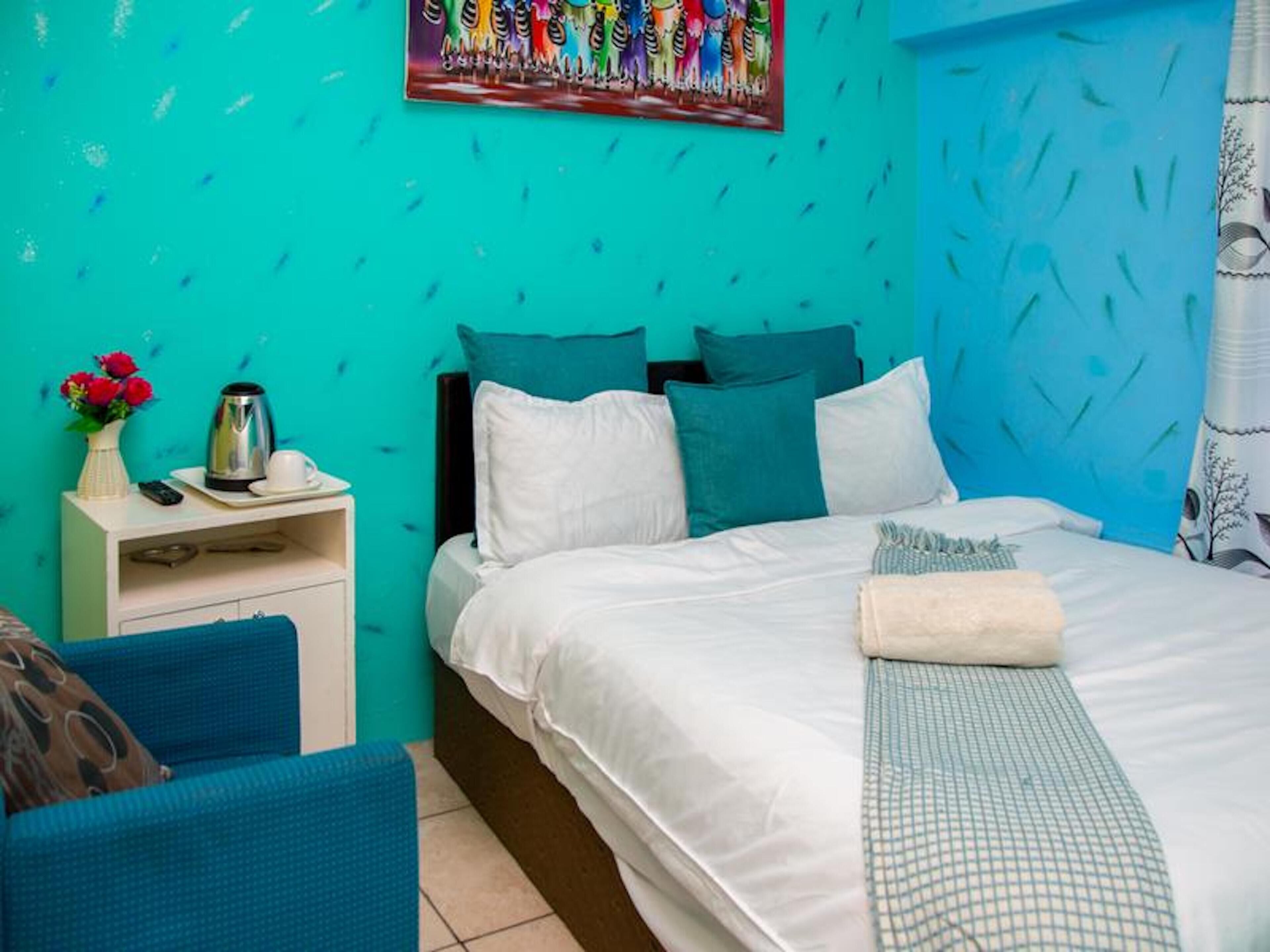 Um quarto com uma cama, uma mesa de cabeceira, uma cadeira e um quadro na parede.