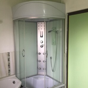Box de chuveiro com porta de vidro, painel de controle e chuveiro manual.