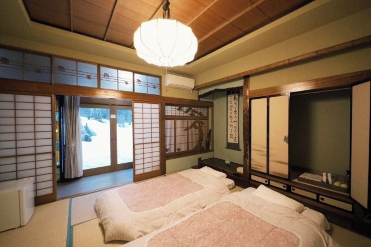 Um quarto tradicional japonês, com tatames, uma porta de shoji e uma porta deslizante para uma varanda.