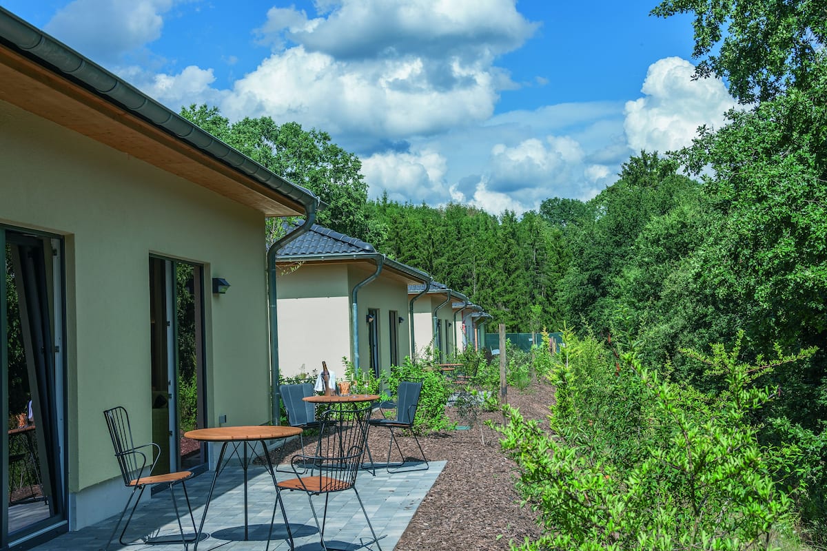 Área de pátio com mobiliário para áreas externas e vista para uma área arborizada.