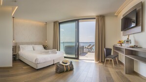 Quarto de hotel com uma cama grande, uma mesa com cadeira, televisão e varanda com vista.