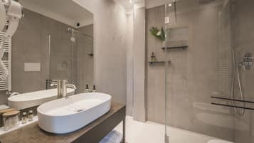 Uma casa de banho moderna com uma grande pia oval, uma cabine de duche em vidro e uma sanita.