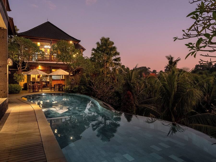Uma área à beira da piscina com deck de madeira, espreguiçadeiras e guarda-sóis.