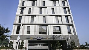 Um hotel moderno com um sinal de estacionamento e a indicação 'Rian', que representa um restaurante.