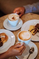 Uma mesa com duas xícaras de café e um prato com um pastel.