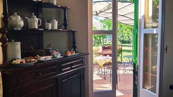 Cozinha com armários de madeira escura, bancada com bules e vista para um pátio externo através de uma porta de vidro.