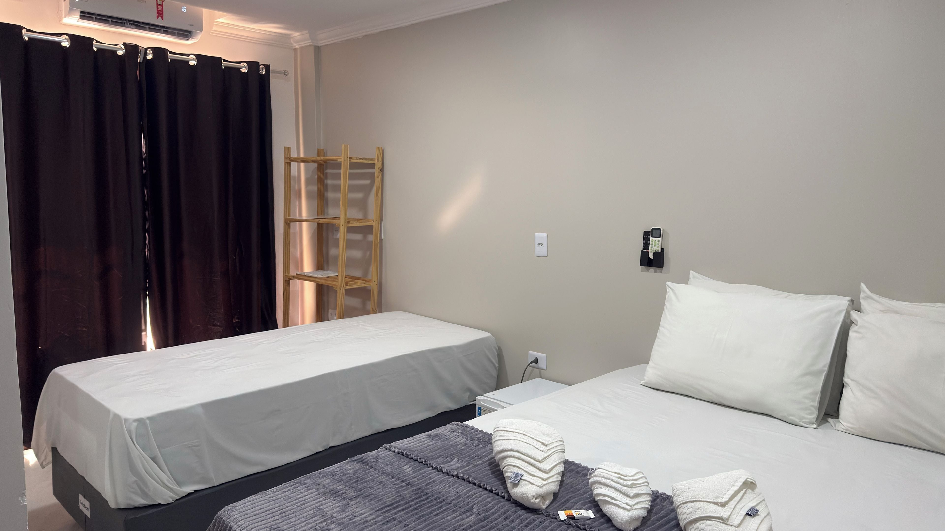 Quarto de hotel com duas camas, uma escada de madeira, um telefone e uma mesinha de cabeceira.