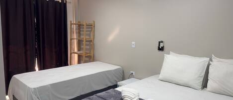 Quarto de hotel com duas camas, uma escada de madeira, um telefone e uma mesinha de cabeceira.