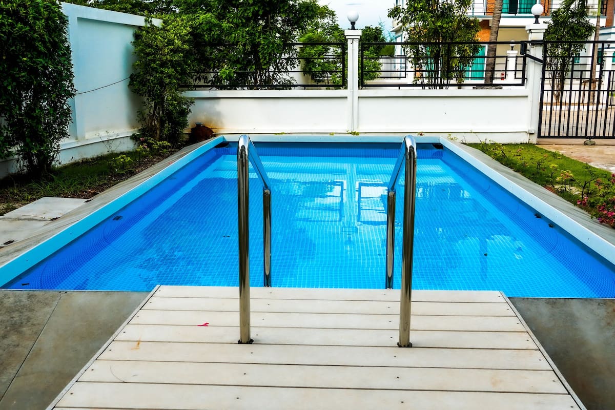 Piscina retangular com área de deck revestida em frente.