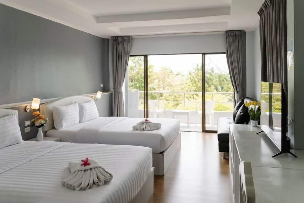Quarto de hotel com duas camas, varanda e televisão.