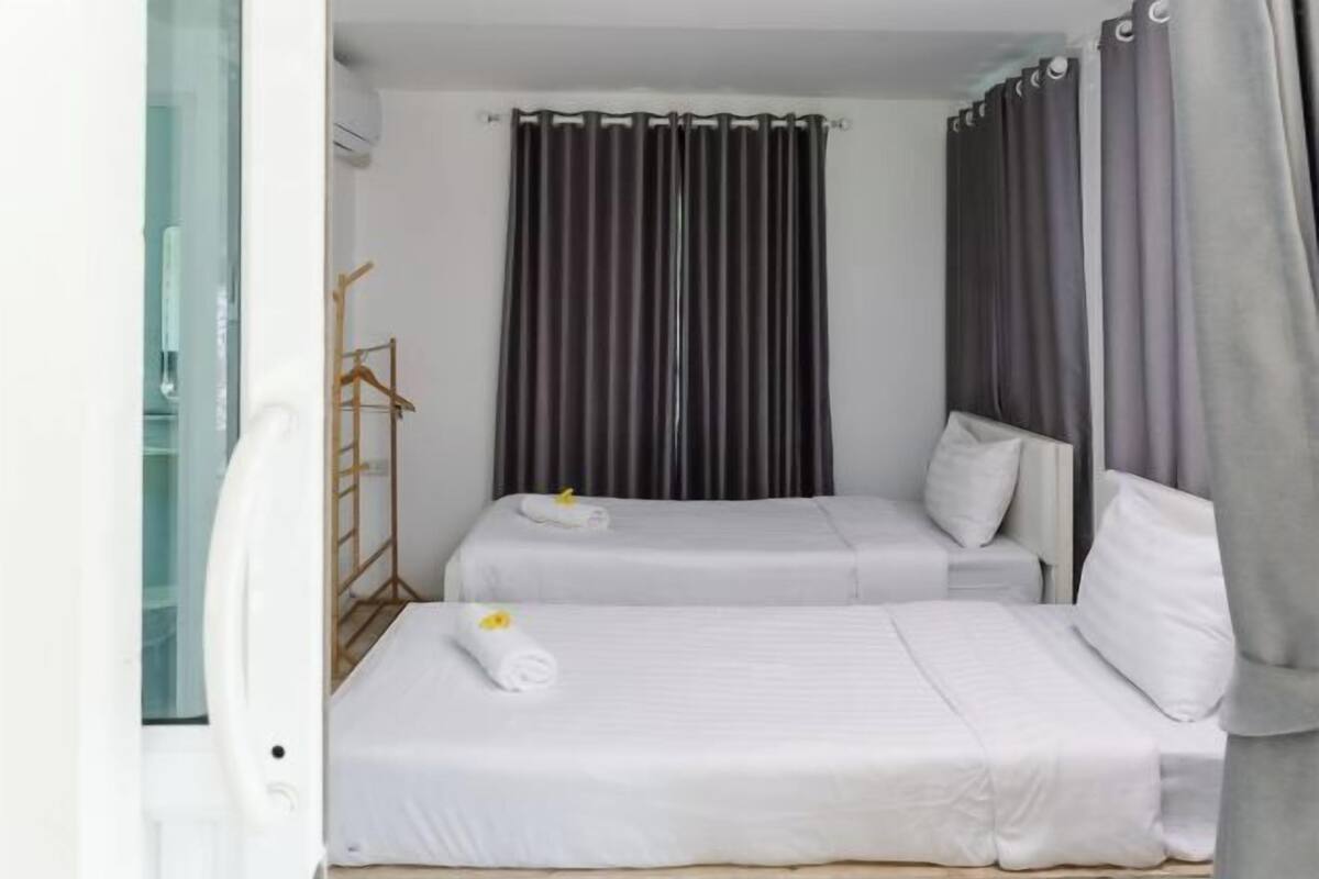 Quarto com duas camas, um guarda-roupa de madeira e uma cortina.