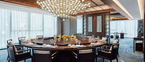 Uma sala de jantar moderna com mesa redonda, cadeiras e um lustre.