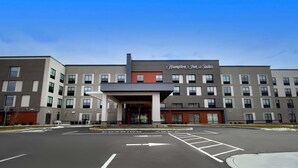 Um hotel moderno com uma entrada imponente, vários andares e céu claro.