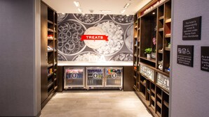 Quarto de hotel com minibar, parede com o letreiro 'Treats' e sinalização 'Hilton Worldwide'.