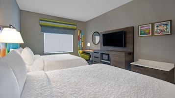 Quarto de hotel com duas camas, televisão, escrivaninha e janela com vista.