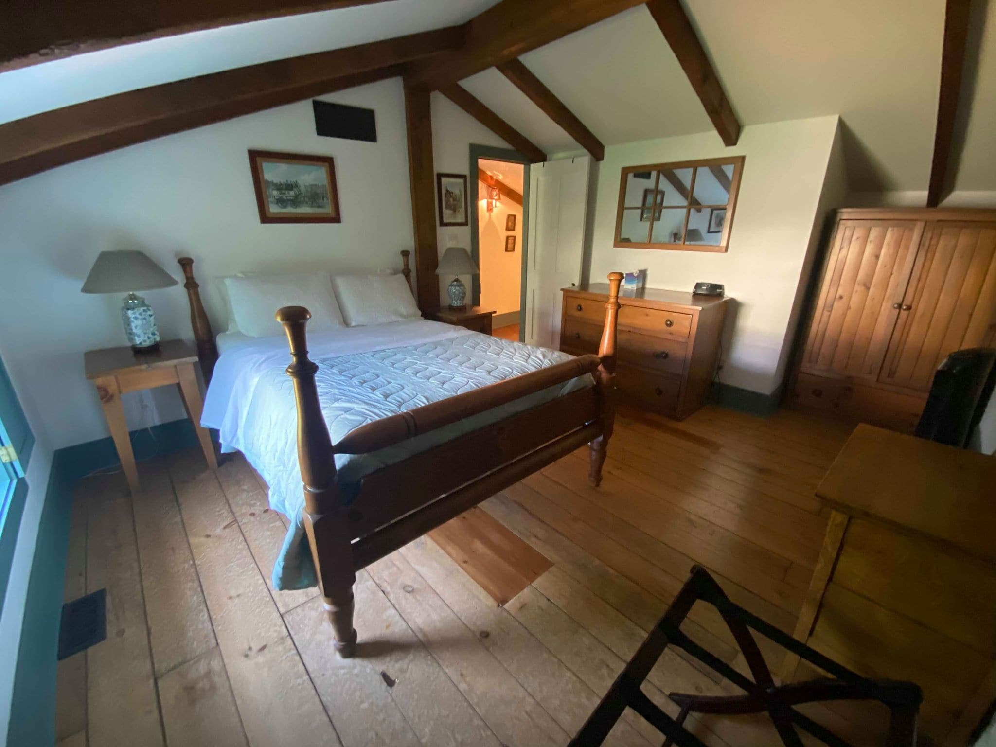 Um quarto com cama de madeira, mesa de cabeceira, penteadeira e espelho.