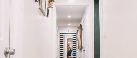 Um corredor com tapete listrado, porta verde e espelho na parede.
