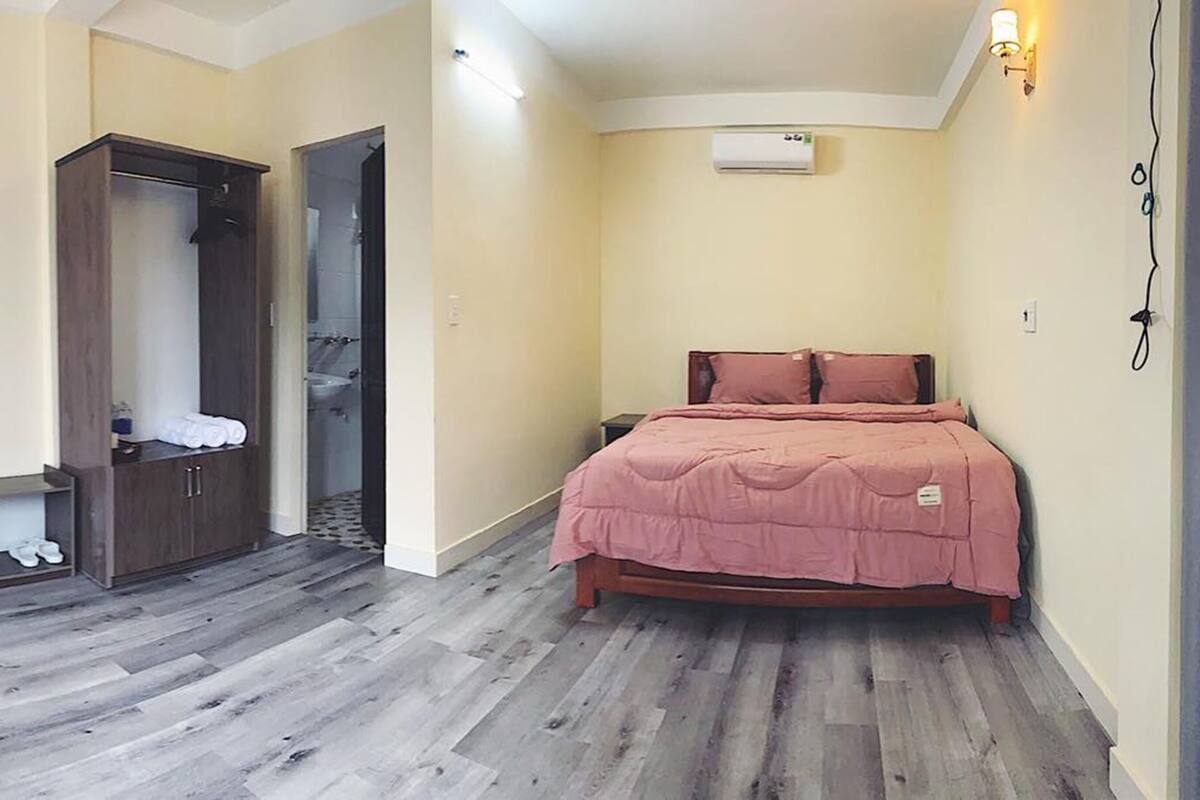 Quarto com uma cama, guarda-roupa, cadeira e uma pequena prateleira.