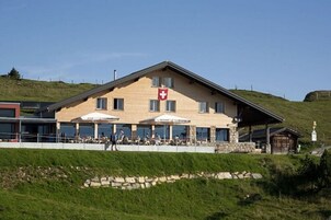 Um edifício com bandeira suíça, mesas ao ar livre e fachada de pedra.