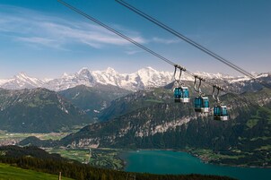 Sistema de teleférico com paisagem montanhosa e um lago ao fundo.