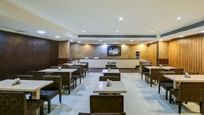 Um restaurante com várias mesas, cabines, um balcão e uma tela de televisão na parede.