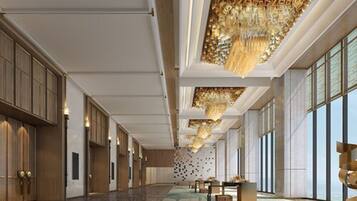 Um amplo hall de hotel com teto alto, janelas grandes e um lustre decorativo.