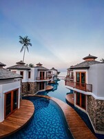 Resort com várias villas interligadas por uma piscina central, com varandas e vista para o mar.