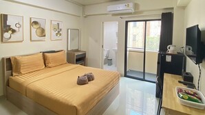 Quarto de hotel com uma cama, uma mesinha com uma cesta, uma televisão e um ar condicionado.