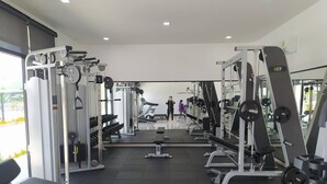 Uma academia com diversos equipamentos de exercício, bancos e suportes para pesos.