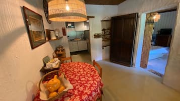 Uma sala de jantar acolhedora com uma mesa posta para dois, uma cesta de laranjas e um candeeiro pendente.