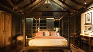 Um quarto aconchegante com uma cama de dossel de madeira, uma escrivaninha com cadeira e uma mesa de cabeceira.