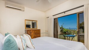 Quarto com cama, cômoda, espelho e varanda com vista.