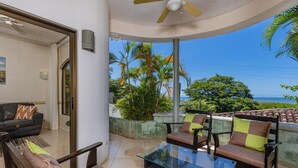Varanda com mesa de vidro, dois sofás com almofadas e ventilador de teto.