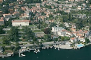 Vista aérea de uma cidade costeira com um porto de recreio, edifícios residenciais e um grande edifício branco com telhado vermelho.