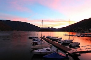 Uma marina com barcos atracados em cais de madeira, cercada por montanhas.