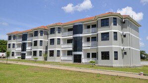 Um edifício residencial com vários andares, varandas e um terraço plano.