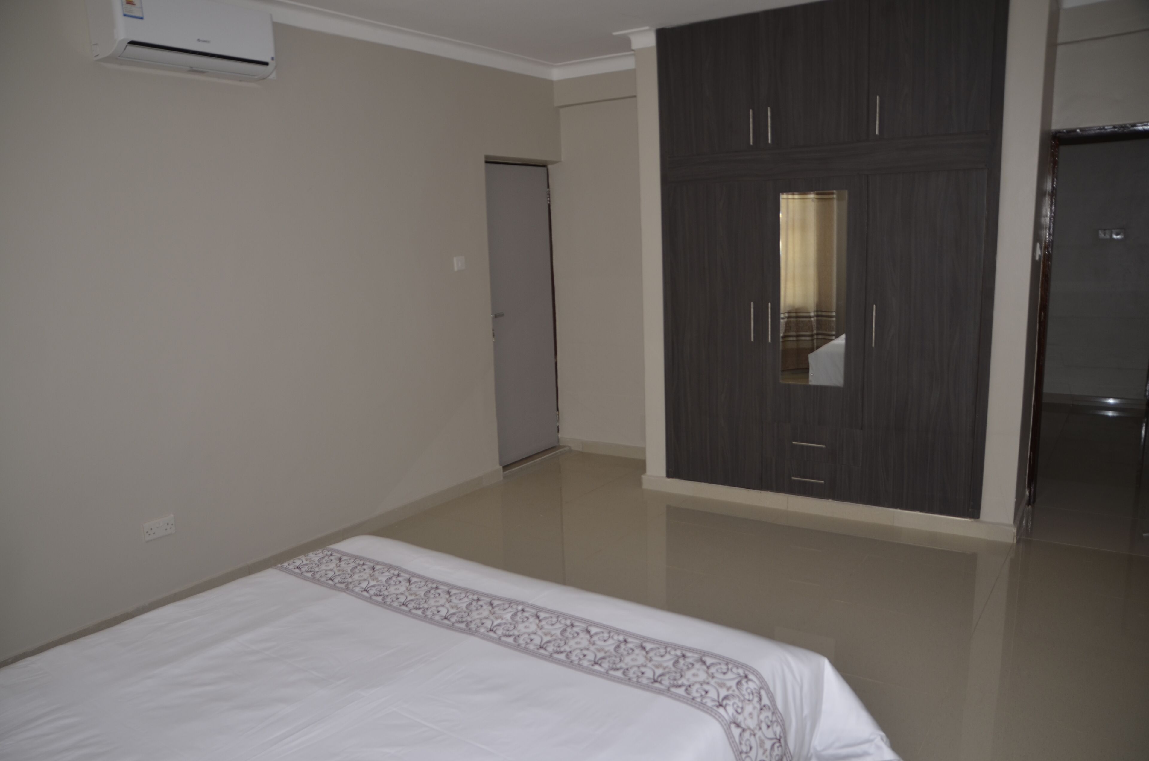 Quarto com cama, guarda-roupa e ar condicionado.